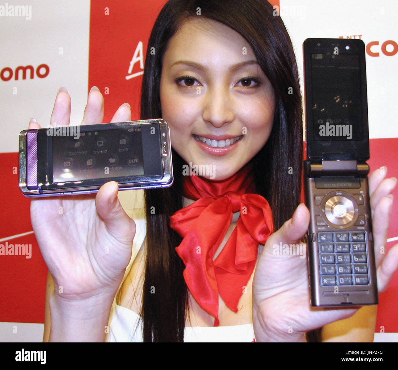 TOKYO, Japan - A woman shows off a new cellphone (R) launched by Japan ...
