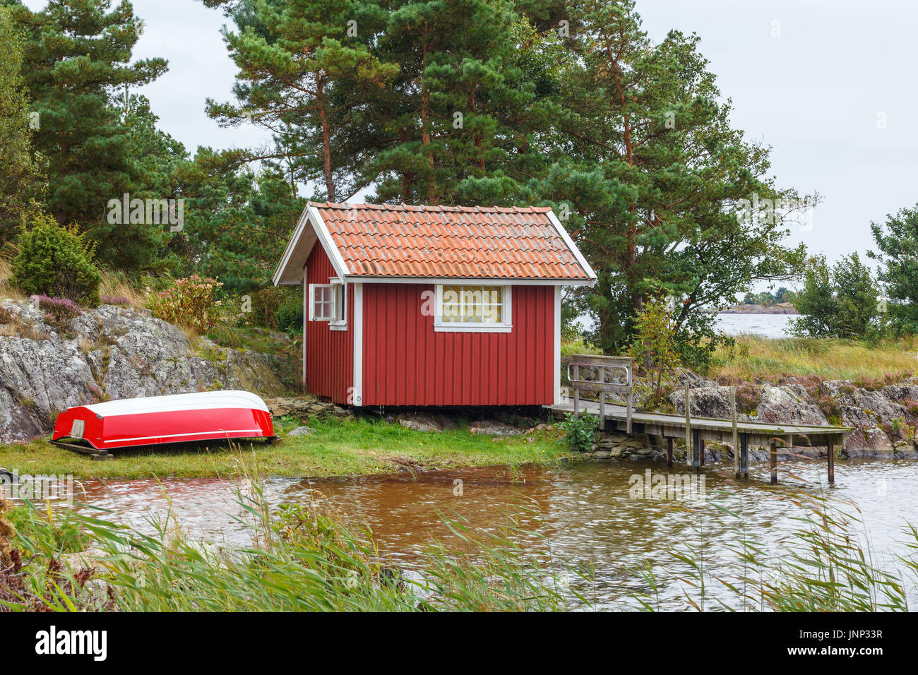 Bath cabin on a beach with a jetty and a rowing boat Stock Photo - Alamy