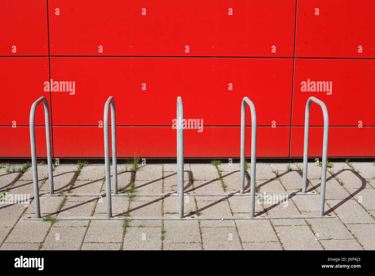 metal Bicycle stand, red house wall Stock Photo - Alamy