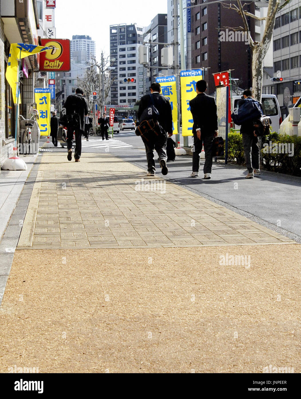 TOKYO, Japan - People walk on a wooden section (L) of a sidewalk in ...