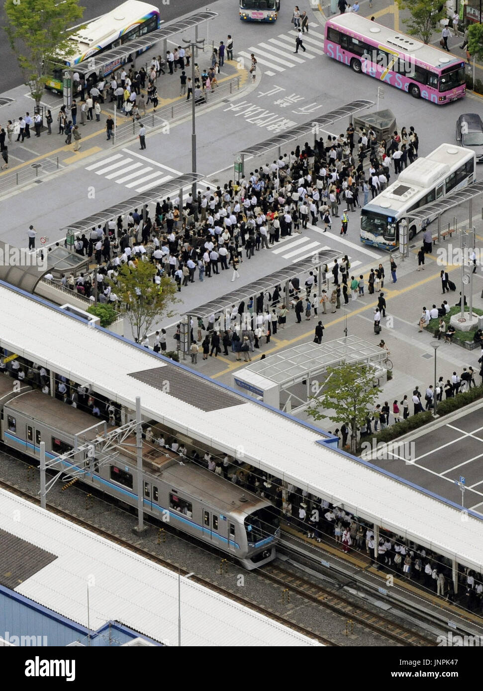 TOKYO, Japan - Commuters stand in long lines waiting for buses during ...