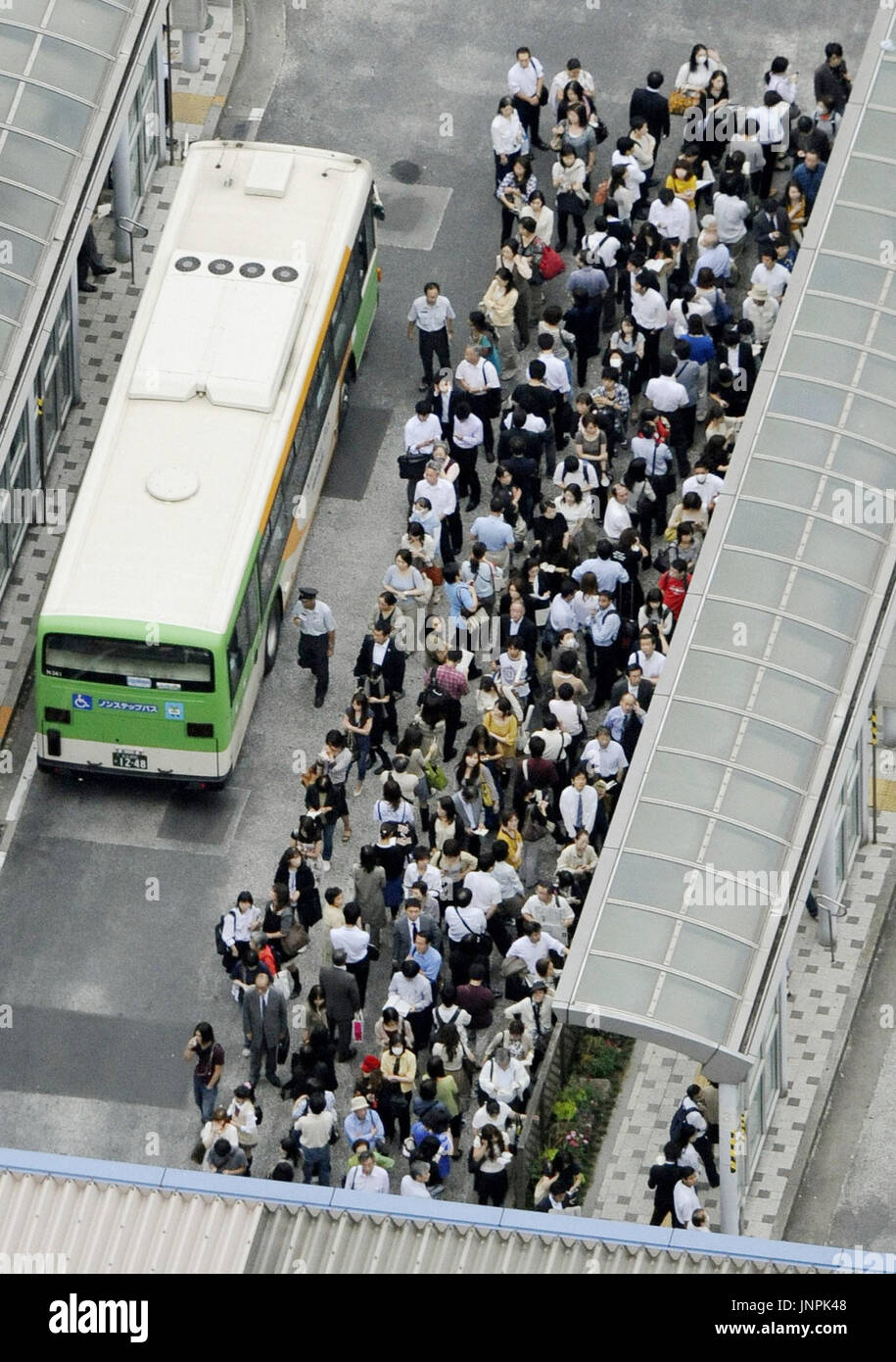 TOKYO, Japan - Commuters stand in long lines waiting for buses during ...