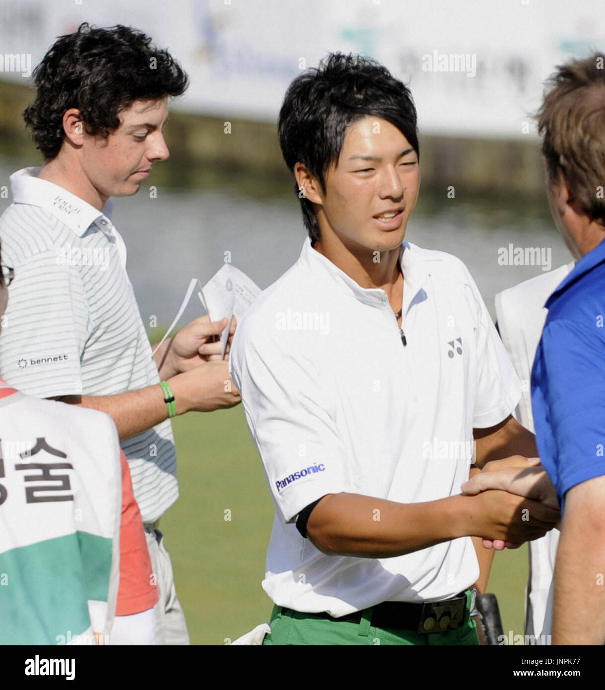 CHEONAN, South Korea - Japanese teenage golfer Ryo Ishikawa (C) shakes hands with his caddie ...