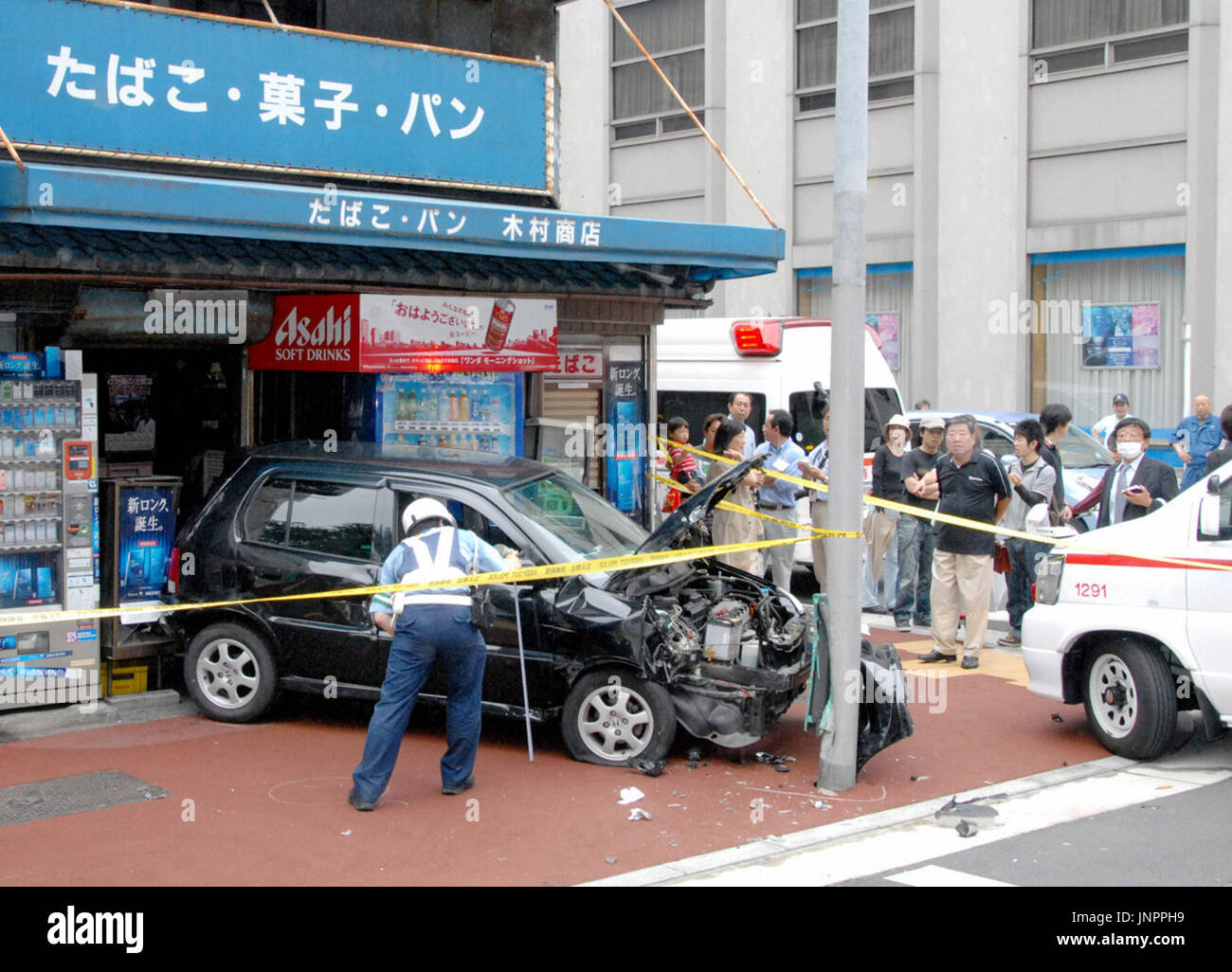 KYOTO, Japan - A police officer examines a passenger car that crashed ...
