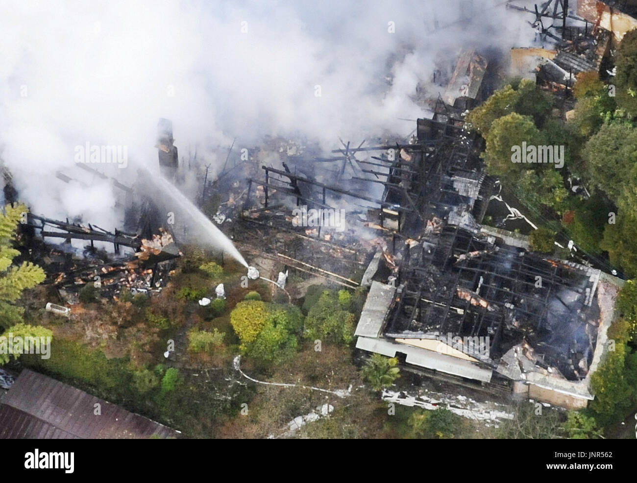 TOKYO, Japan - Firefighters try to put out a fire at what remains of a ...