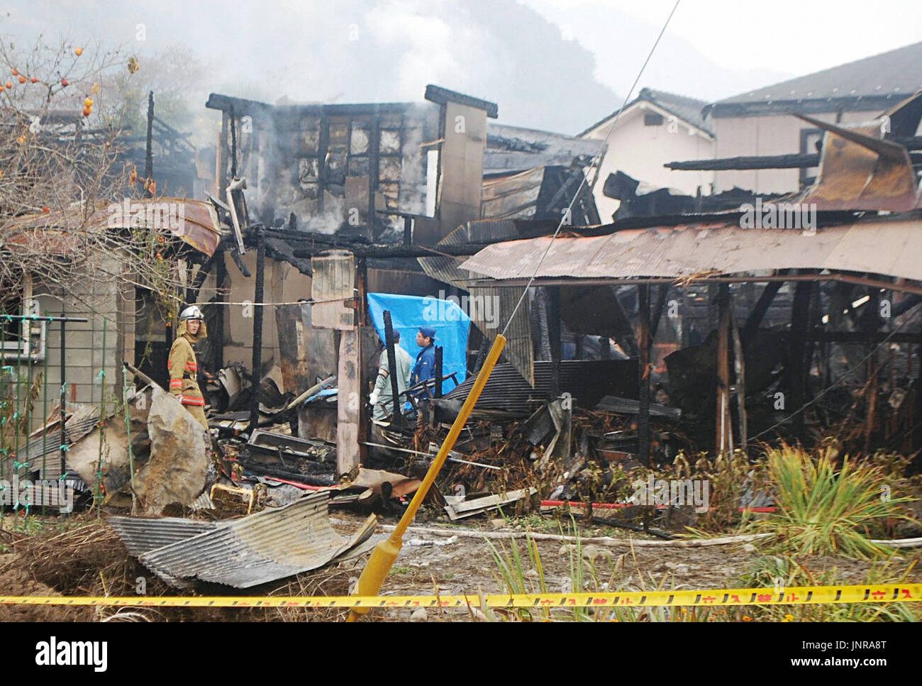 NIIMI, Japan - Firefighters and police inspect a house in Niimi ...