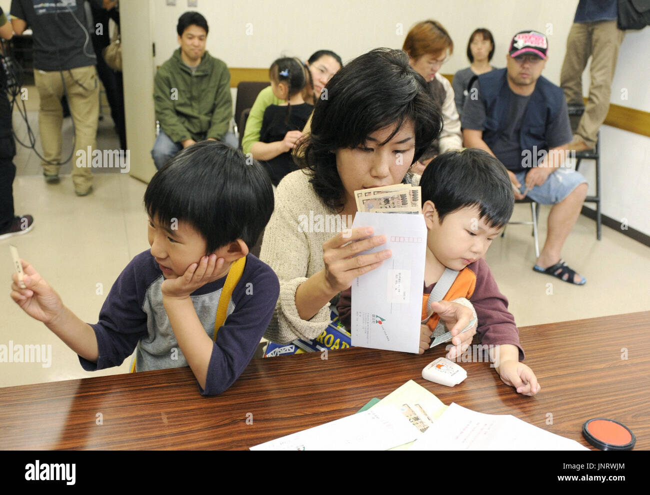 ASAHI, Japan - A mother checks the allowance she received under a new ...