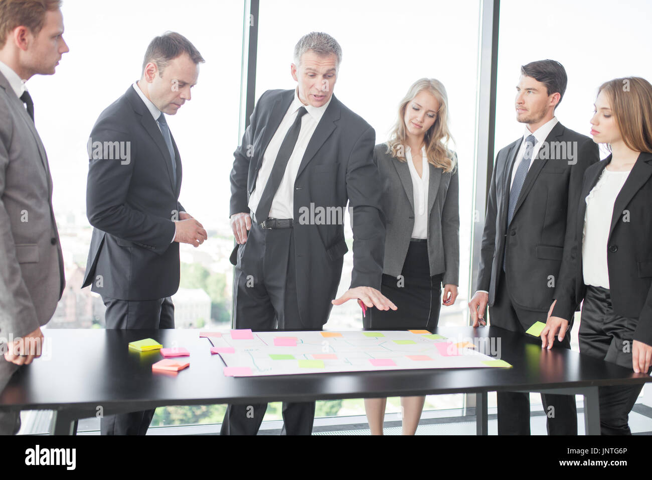 Business people team developing plan on office desk using stick notes ...
