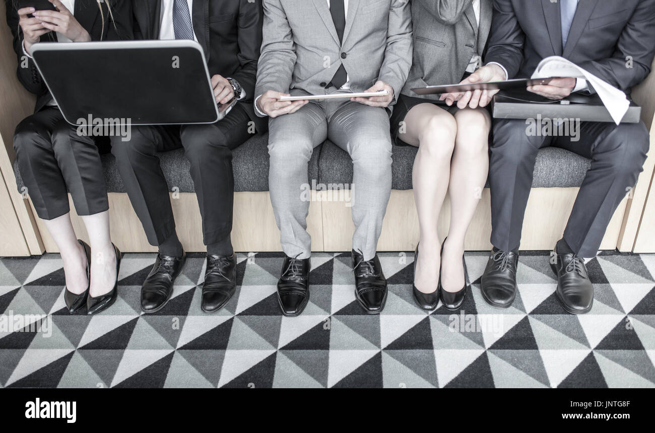 Business people working together sitting in a row in lobby and holding ...