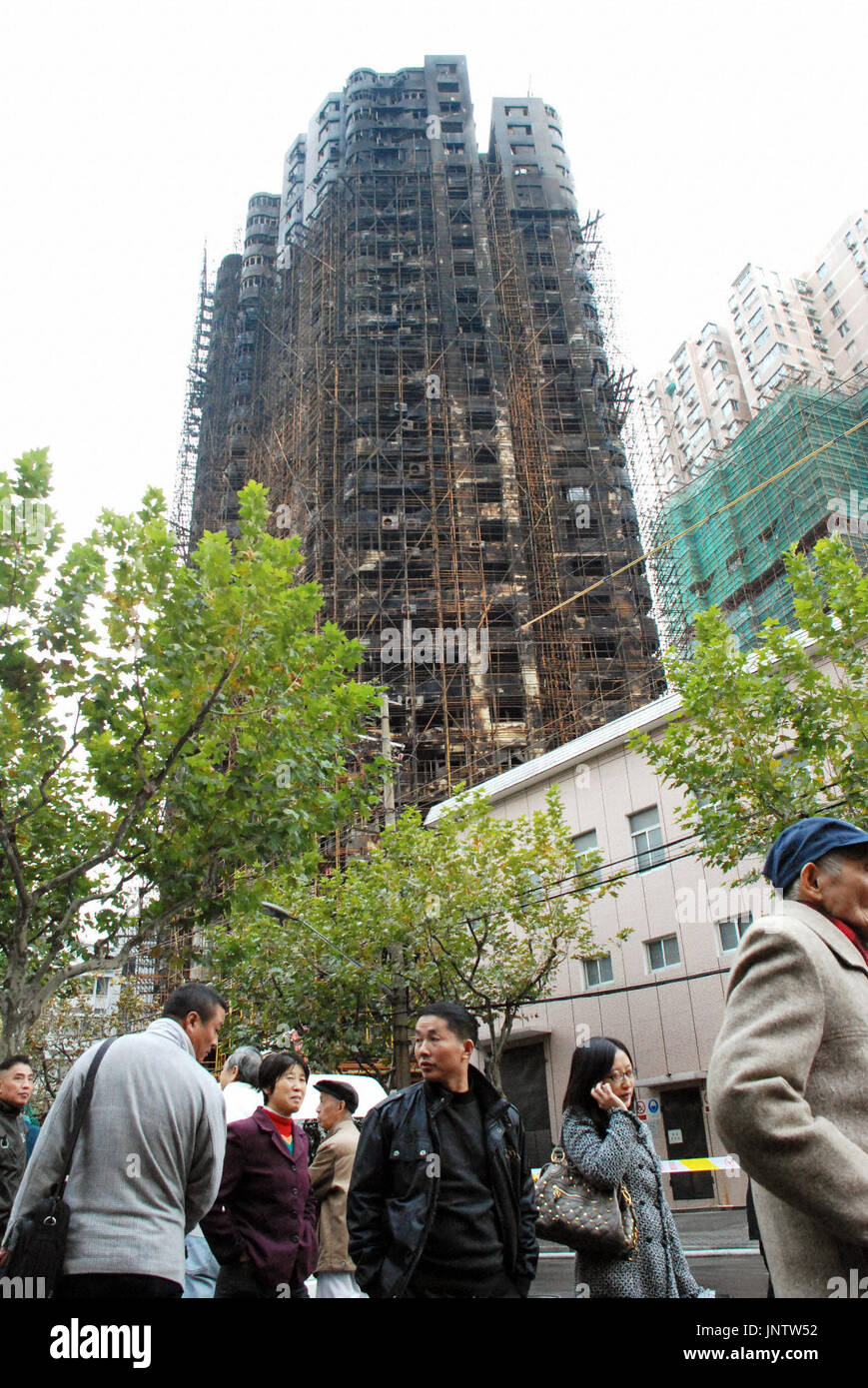 SHANGHAI, China - People pass by a high-rise residential tower scorched ...