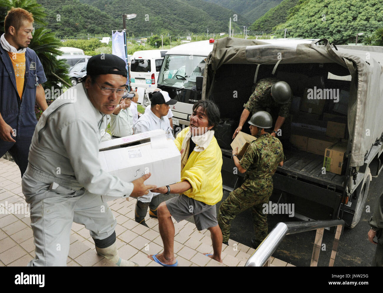 AMAMI, Japan - People carry relief goods to a shelter from a truck of ...