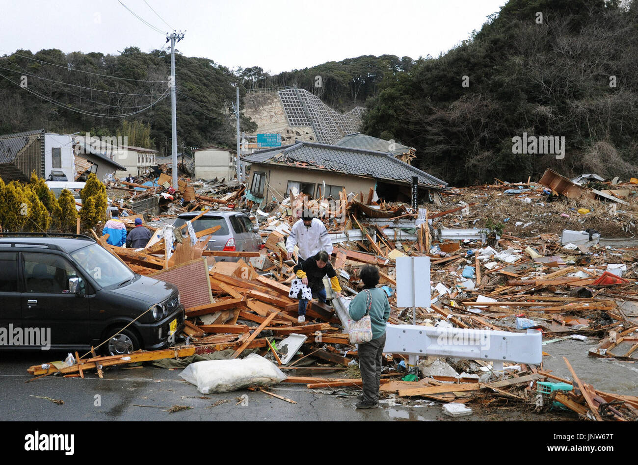 IWAKI, Japan - People walk over the debris of houses after a powerful ...