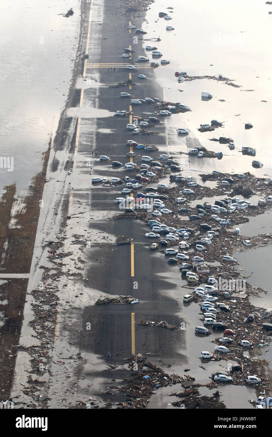 SENDAI, Japan - Vehicles and mud swept by tsunami cover a runway at ...