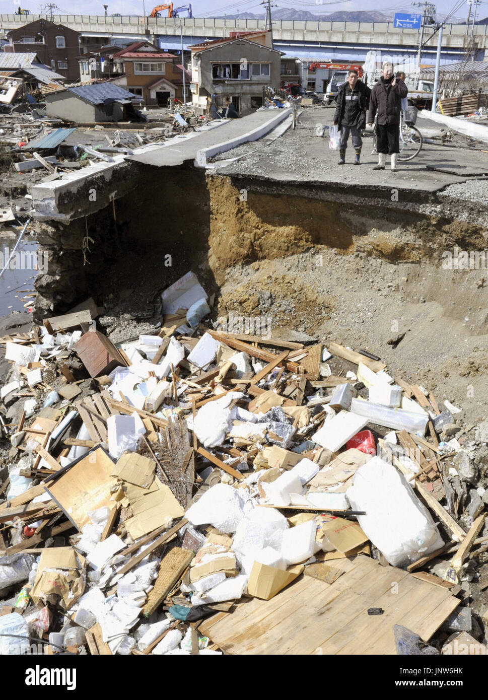 MIYAKO, Japan - People stand in front of a partially collapsed road in ...
