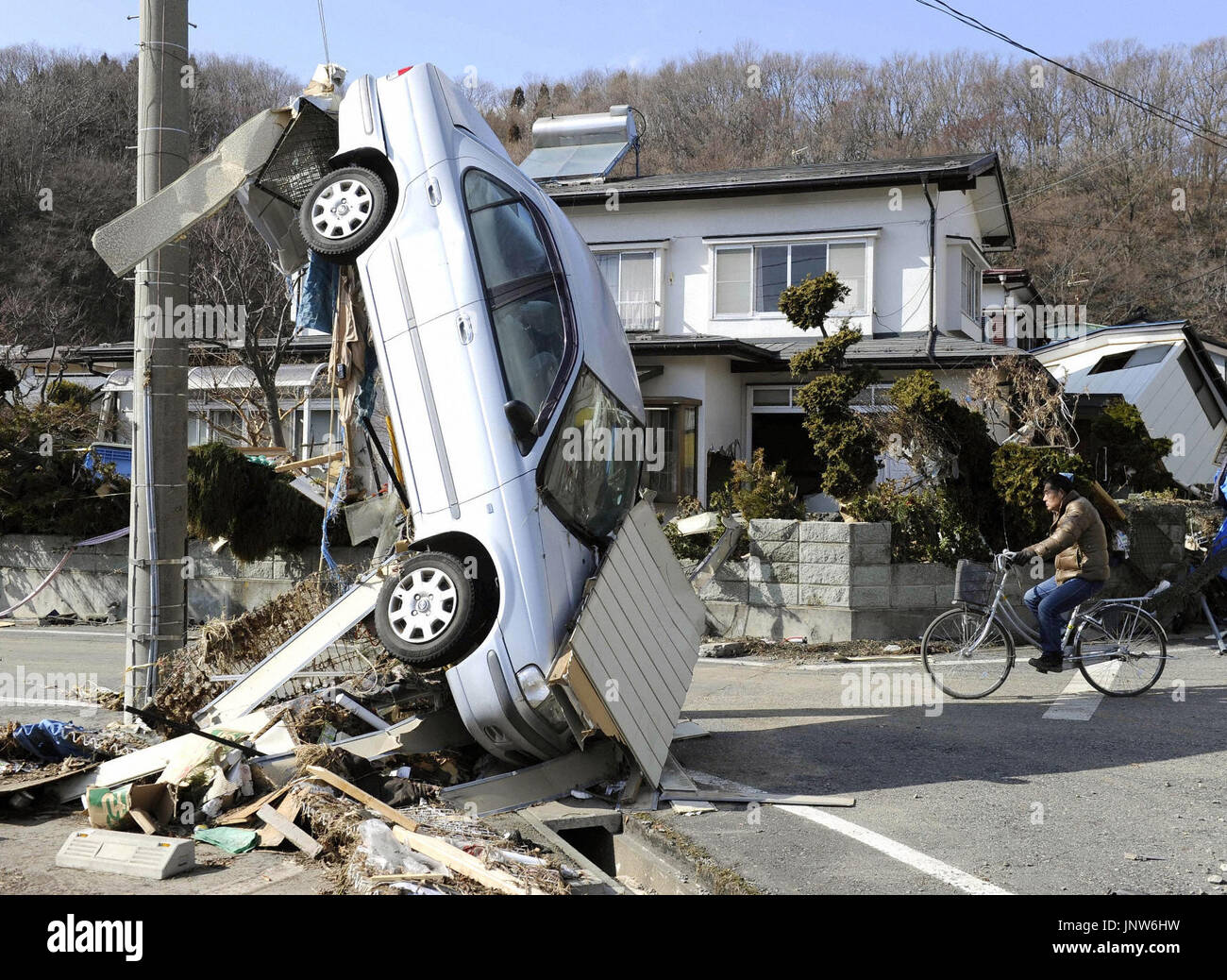 MIYAKO, Japan - A bicycle rider passes by a car wreck in Miyako, Iwate ...