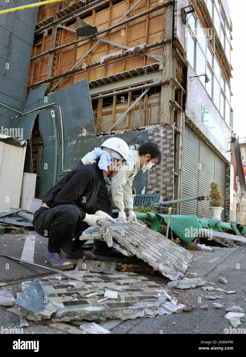 FUJINOMIYA, Japan - Workers remove debris fallen from a building in ...
