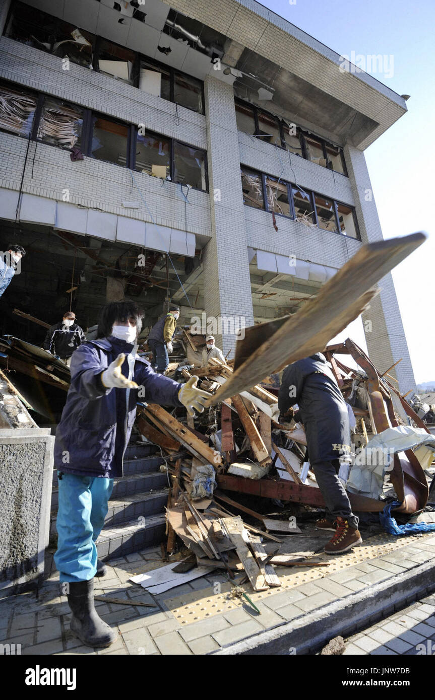 ONAGAWA, Japan - People clear rubble at a damaged public facility in ...