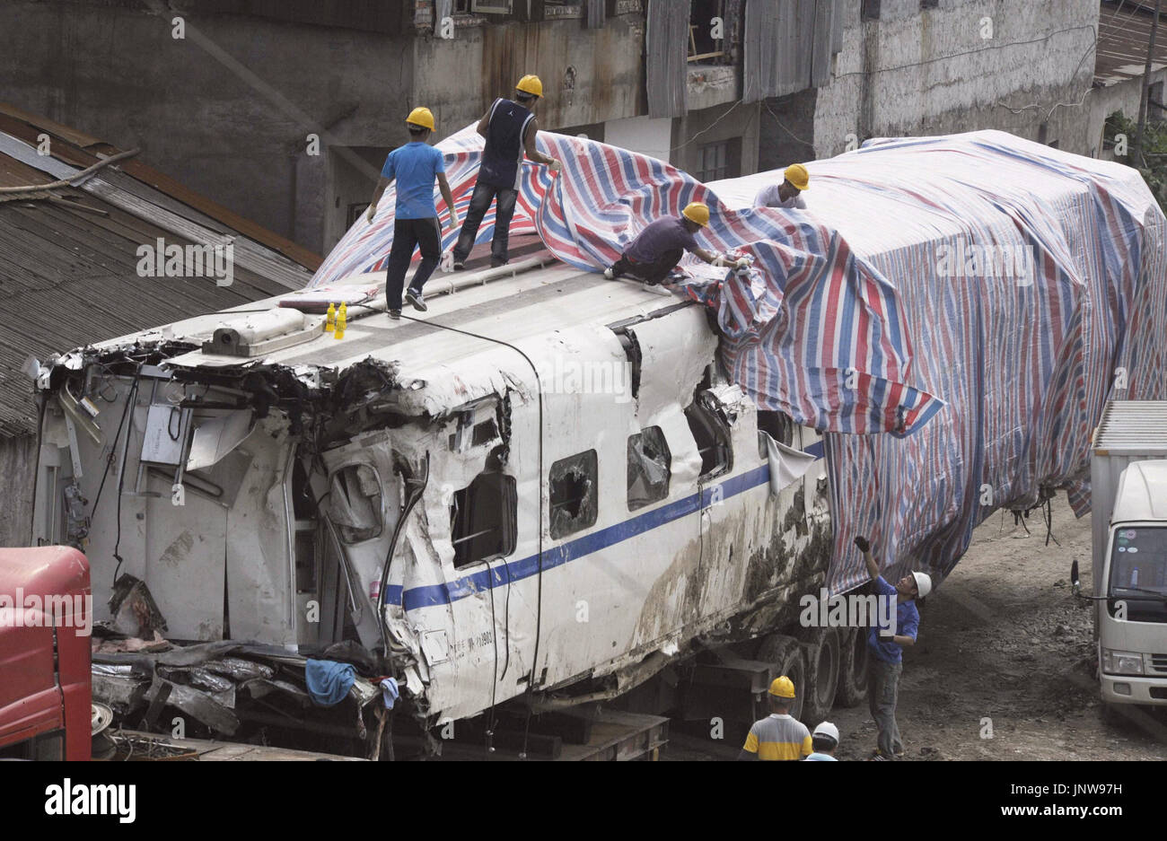 WENZHOU, China - Workers cover a damaged train carriage with a sheet on ...