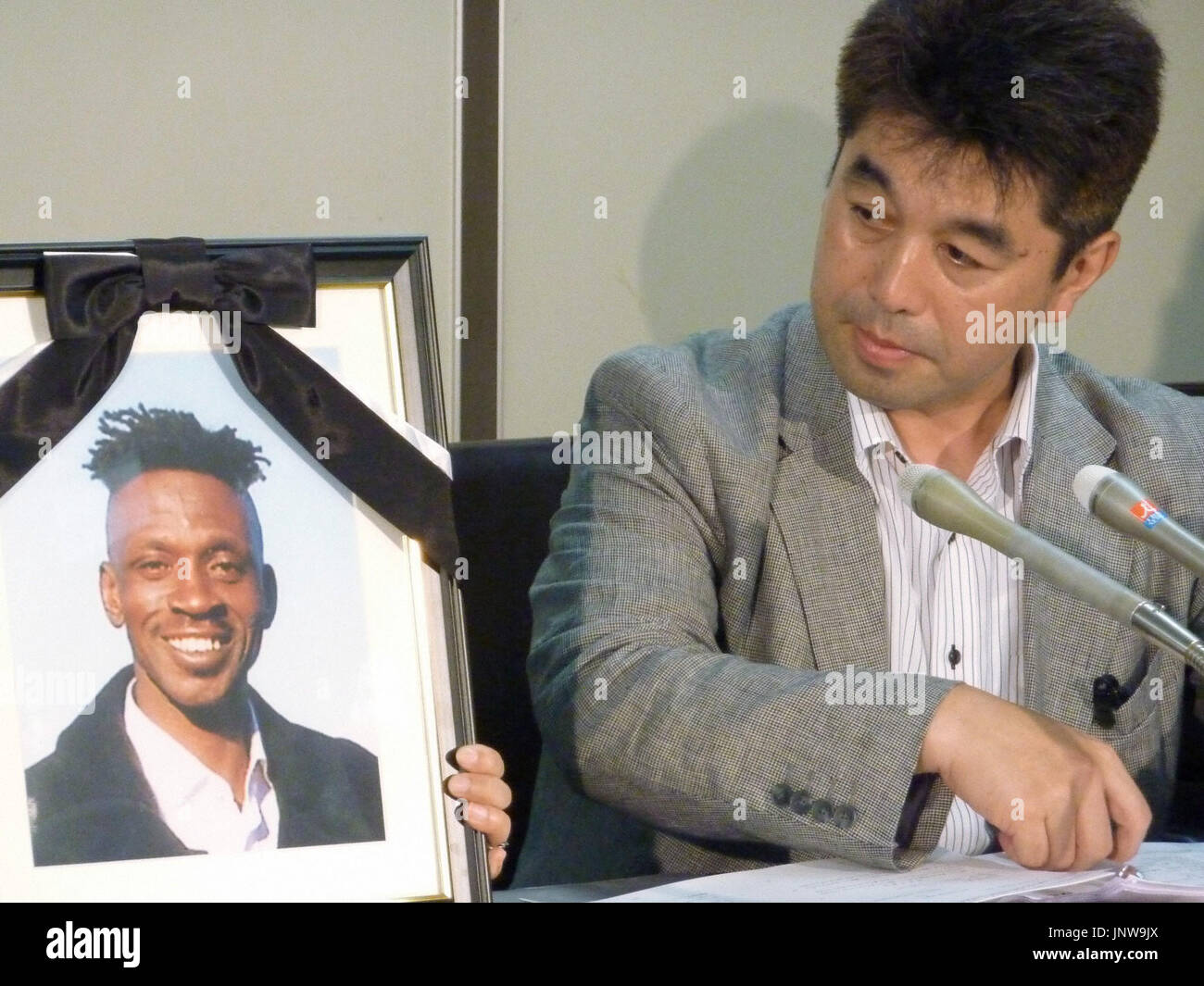 TOKYO, Japan - Lawyer Koichi Kodama (R) looks at a photo of Abubakar Awudu Suraj, a Ghanaian man ...