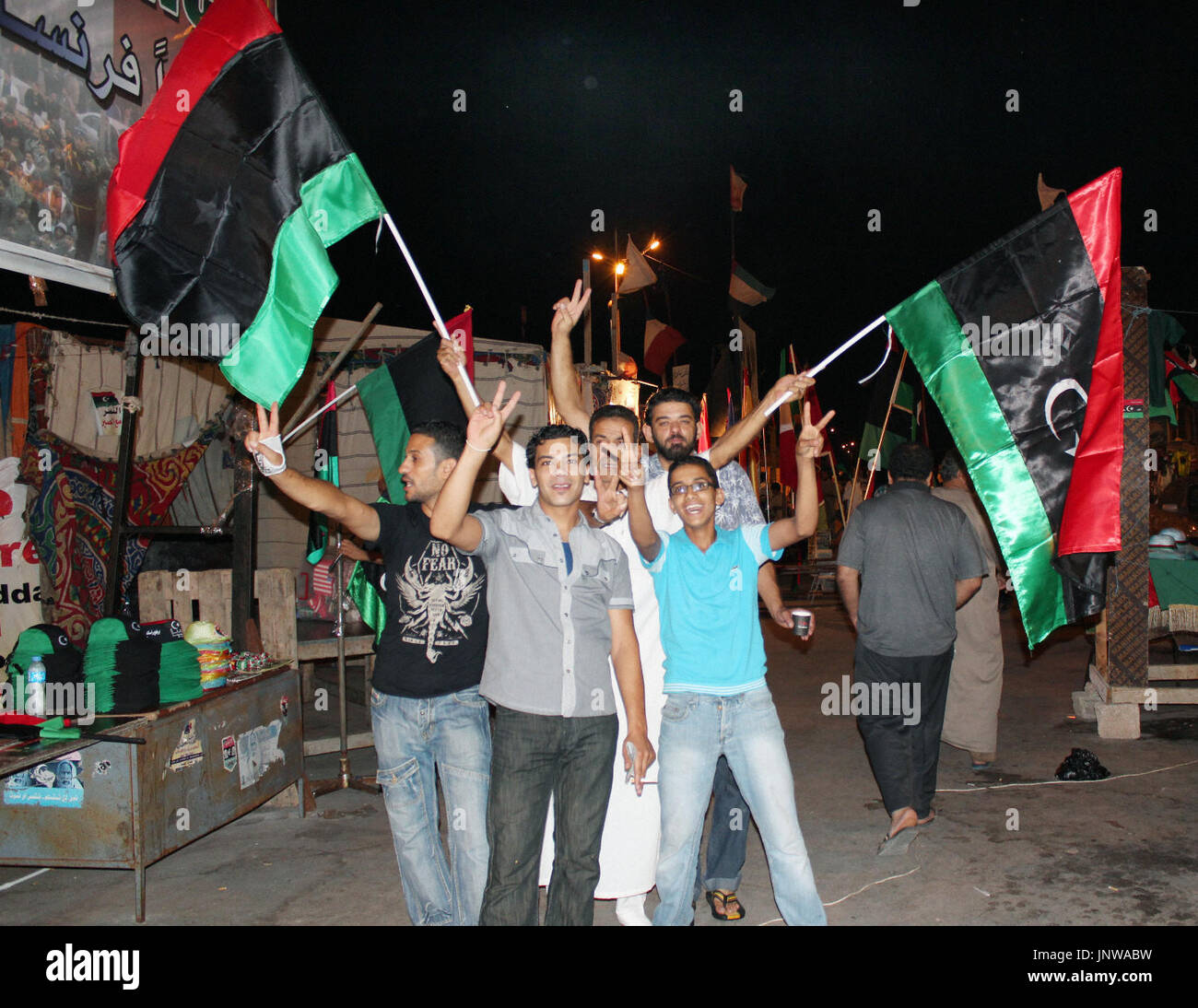 BENGHAZI, Libya - People make V signs and wave tricolor flags of Libyan ...