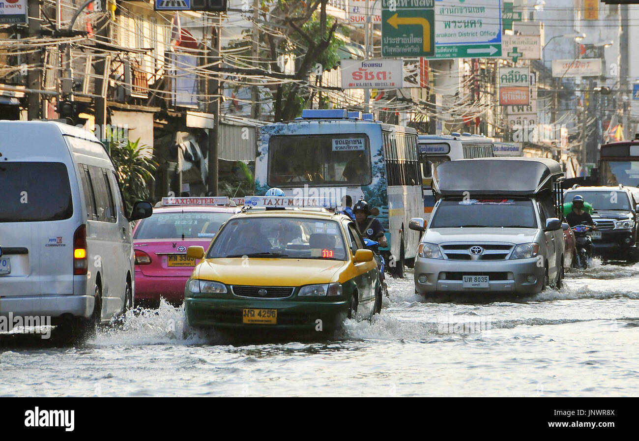 BANGKOK, Thailand - Vehicles run on an inundated street in central ...