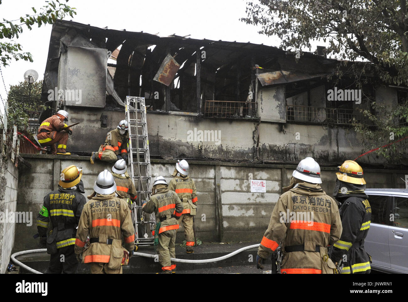 TOKYO, Japan - Firefighters work at a charred wooden apartment house in ...