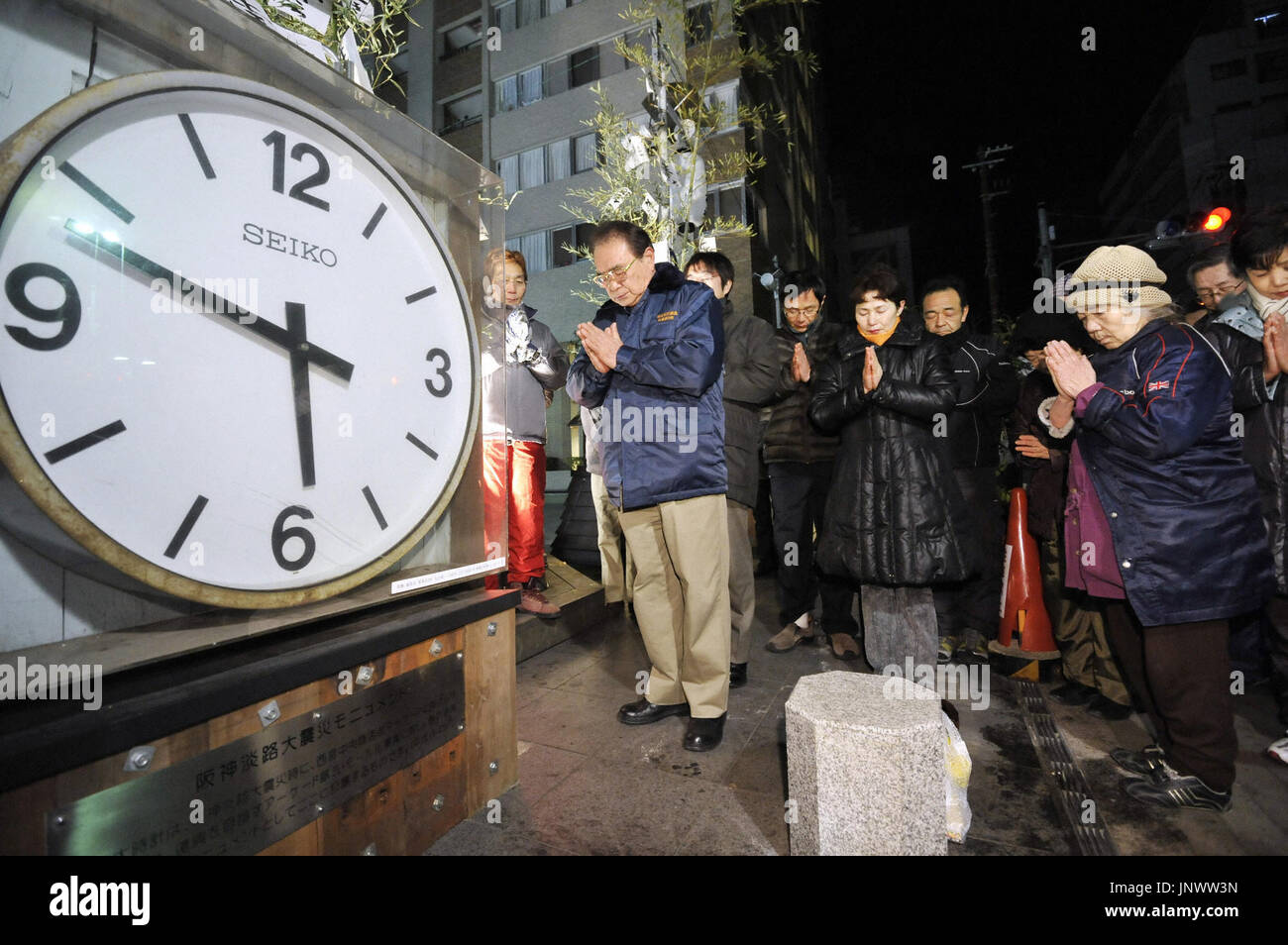 NISHINOMIYA, Japan - People offer a silent prayer around a clock ...