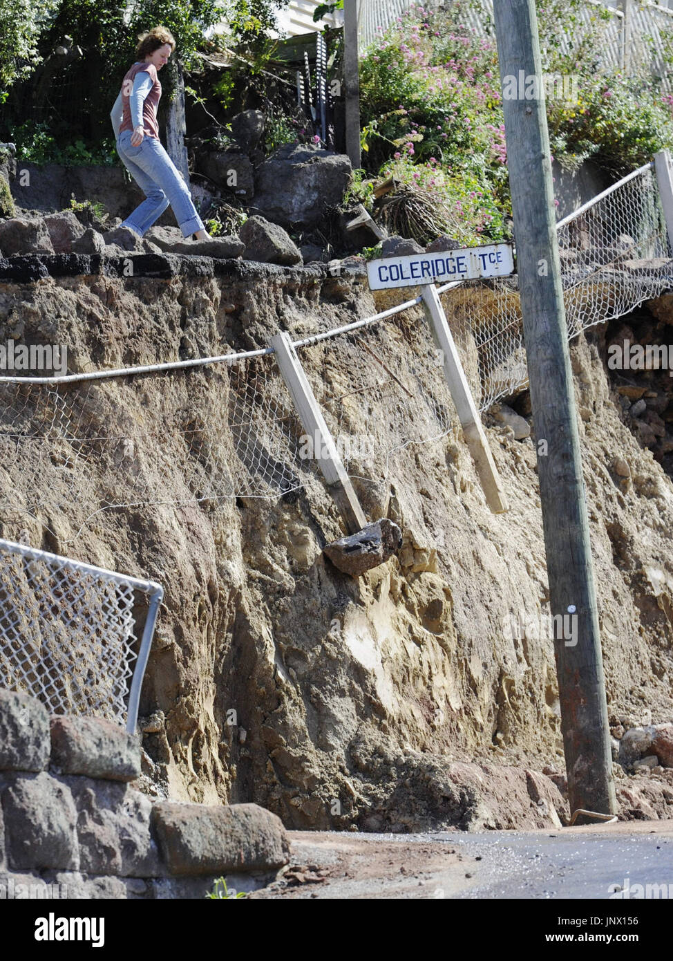 LYTTLETON, New Zealand - A woman walks on a partially collapsed path on ...
