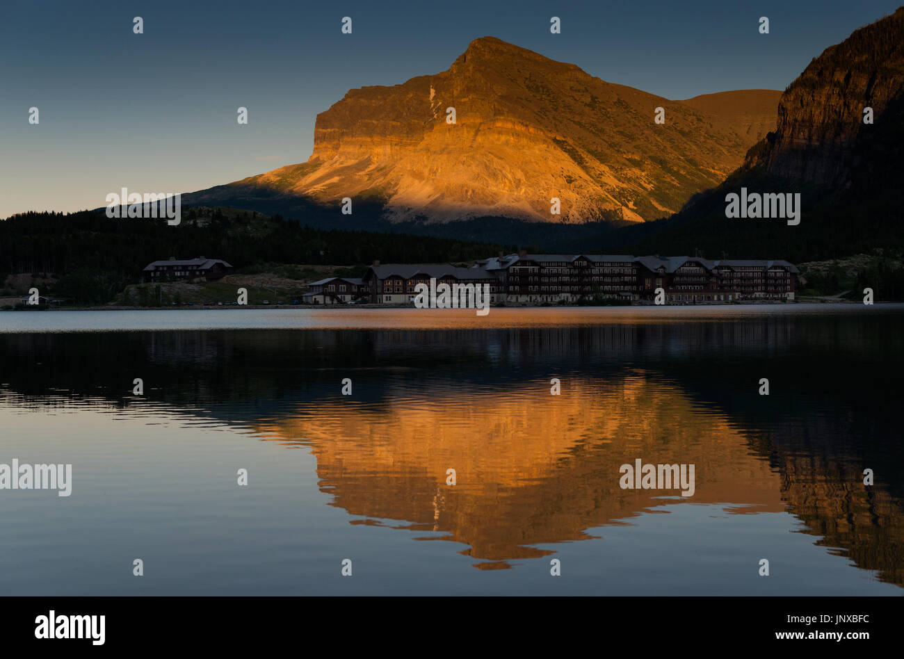 Mirror reflection of mountains in lake water at sunset in Glacier ...