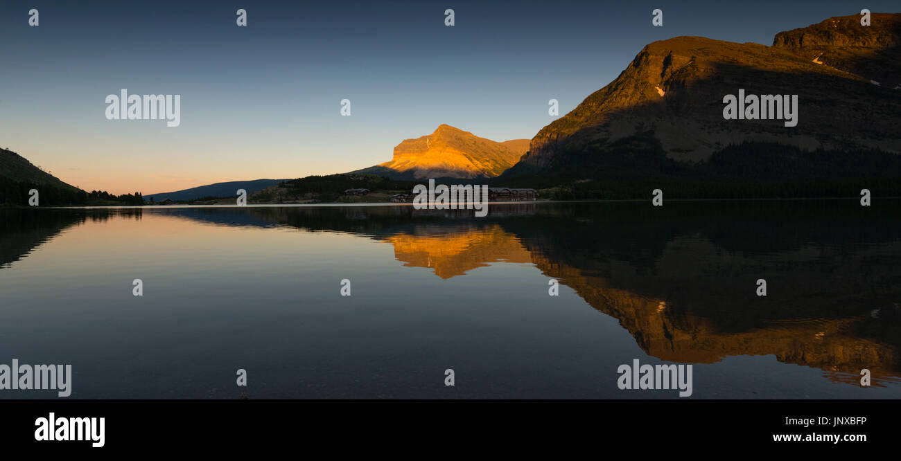 Mirror reflection of mountains in lake water at sunset in Glacier ...