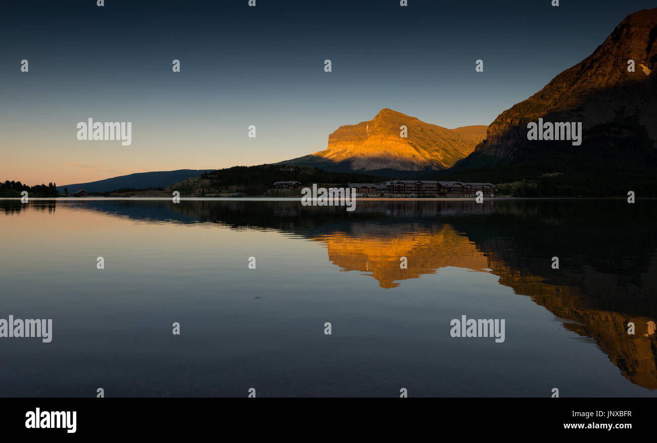 Mirror reflection of mountains in lake water at sunset in Glacier ...