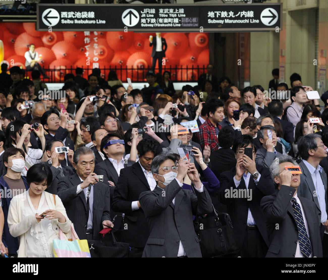 TOKYO, Japan - Commuters look up a solar eclipse in front of Tokyo's ...