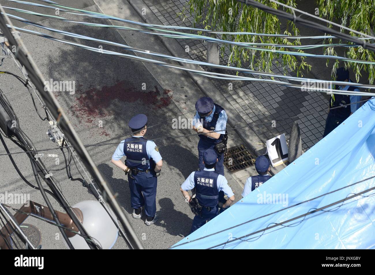 OSAKA, Japan - Police officers stand at the bloodstained scene of a ...