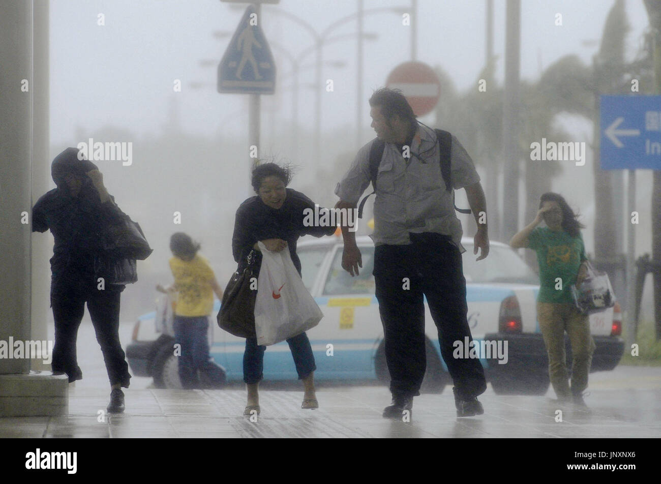 NAHA, Japan - Pedestrians endure strong winds near Naha airport as ...