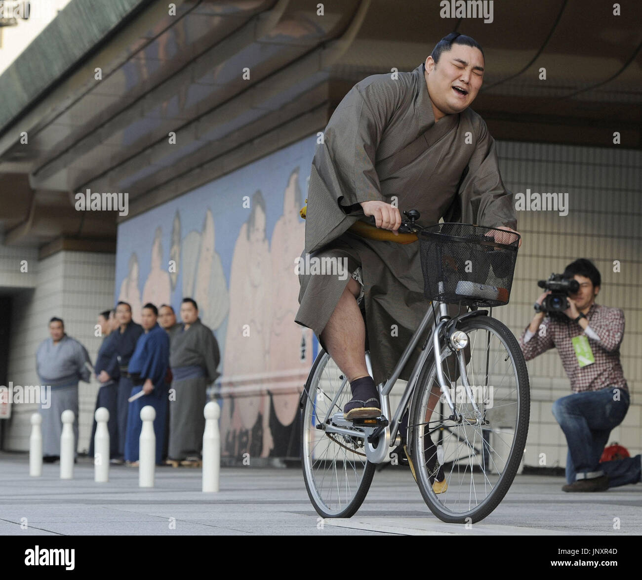 TOKYO, Japan - Sumo wrestler Okinoumi riding on a bicycle loses balance ...