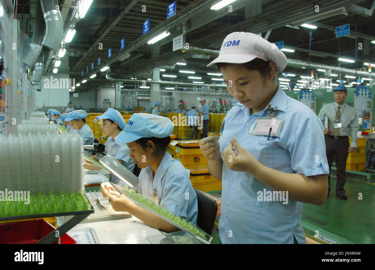 OSAKA, Japan - Factory workers inspect product parts at a Mabuchi Motor ...