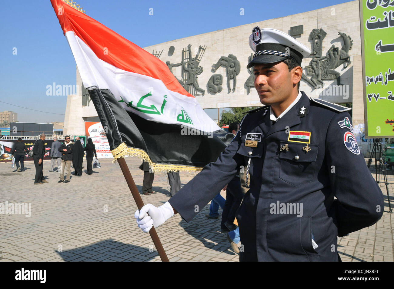 BAGHDAD, Iraq - A police officer holds Iraq's national flag in Baghdad ...