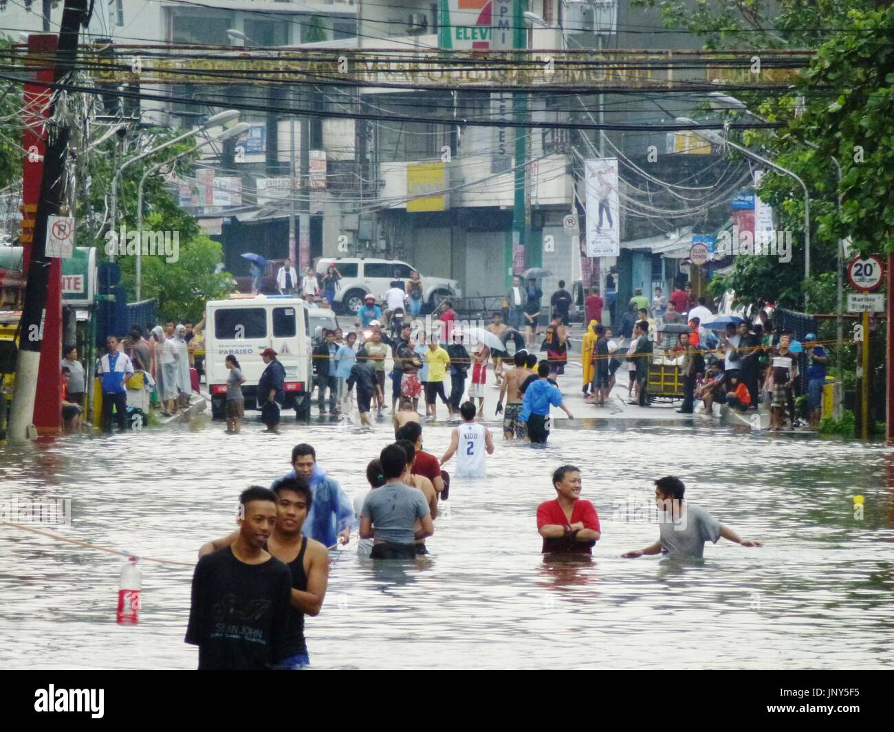 MANILA, Philippines - People wade through a flooded street in Quezon ...
