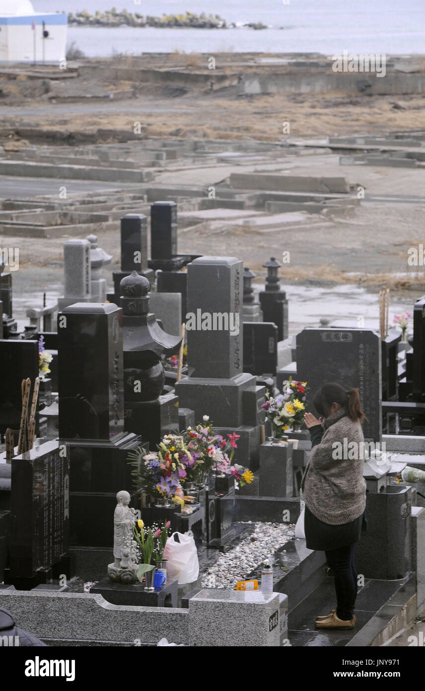 SOMA, Japan - A woman offers a prayer at a graveyard near the sea in ...