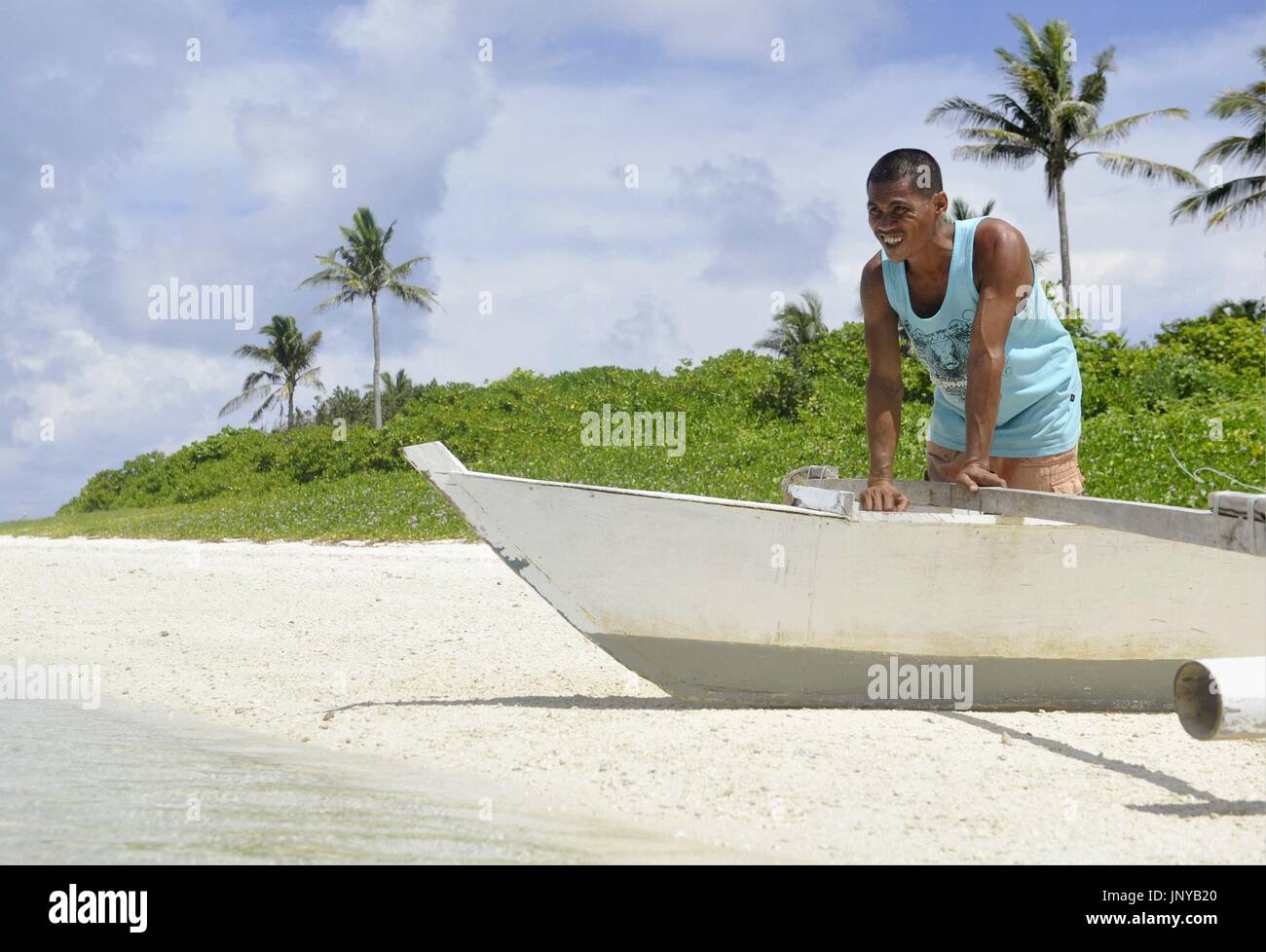 THITU ISLAND, Spratly Islands - A man maintains a boat on a beach on ...