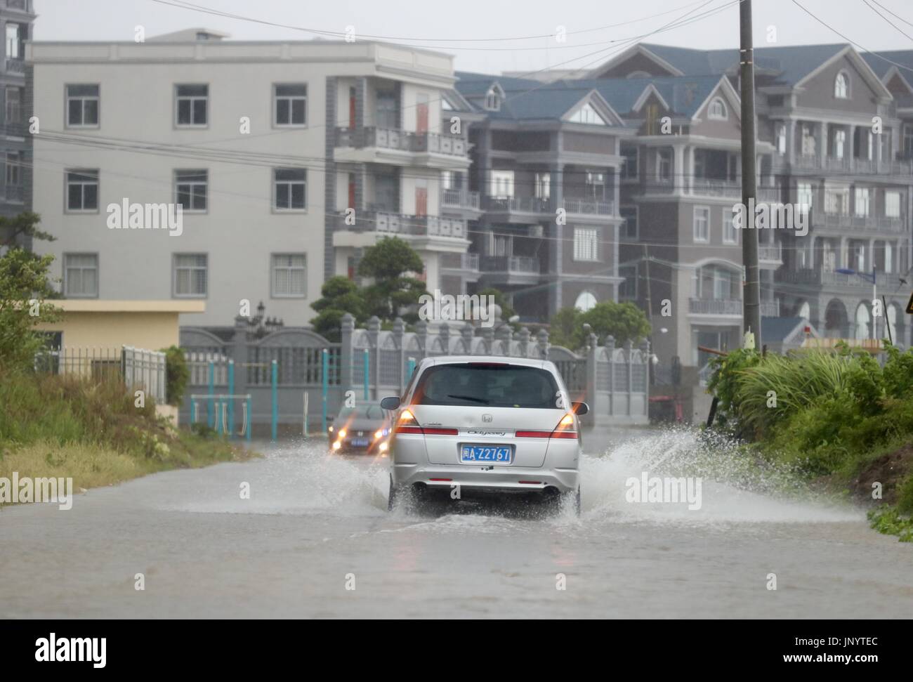 Fuqing, China. 31st Jul, 2017. Cars push through waterlogged road in ...