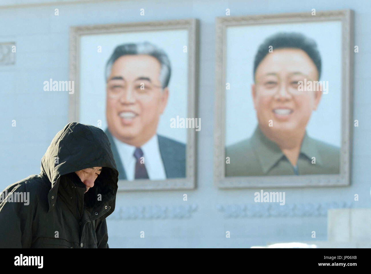 PYONGYANG, North Korea - A man passes portraits of North Korean founder Kim Il Sung and late ...