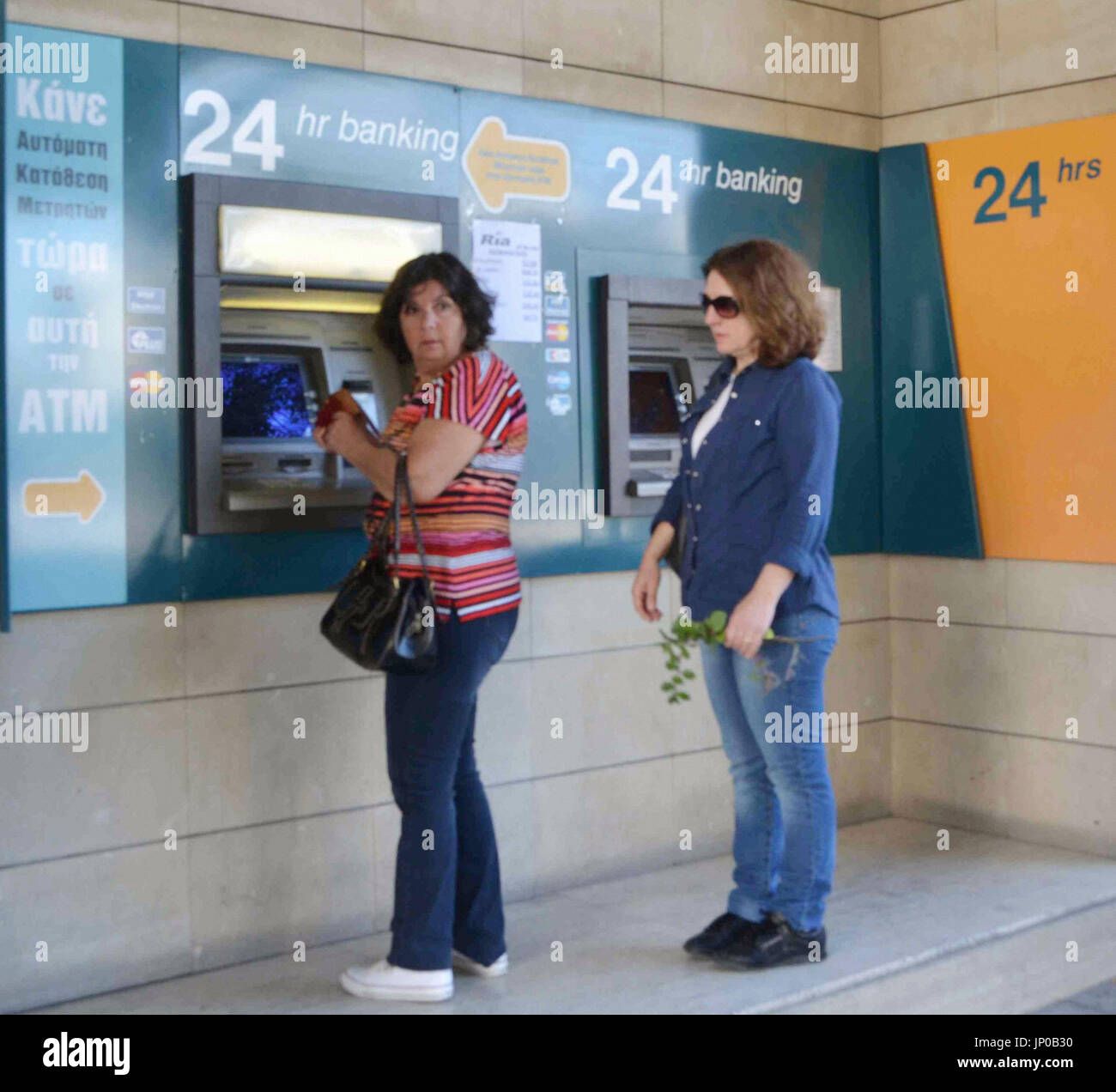NICOSIA, Cyprus - Women visit an ATM corner of a bank in Nicosia on ...