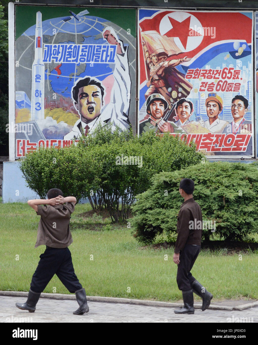 PYONGYANG, North Korea - People pass propaganda signs in Pyongyang ...