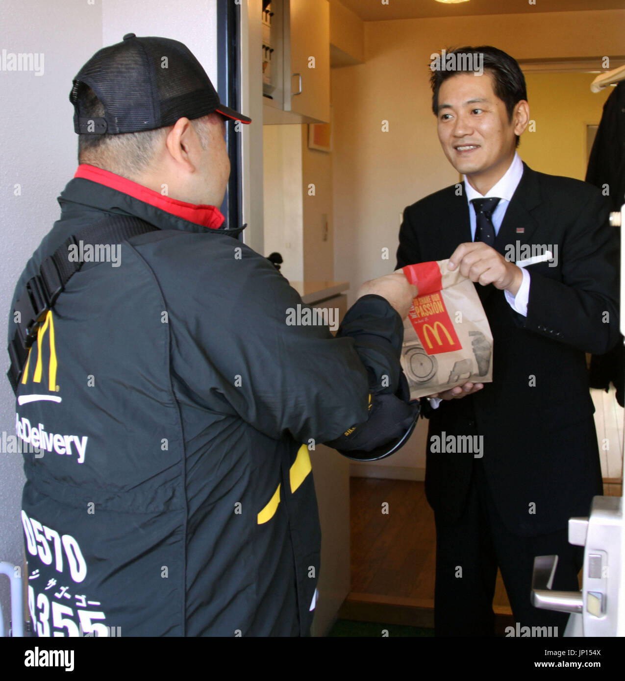 TOKYO, Japan - Yasuhiro Yamamoto, who runs a management consulting business, receives hamburgers ...