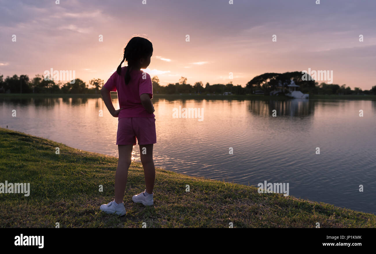 back side of little girl exercise on park with sunset, healthy concept ...