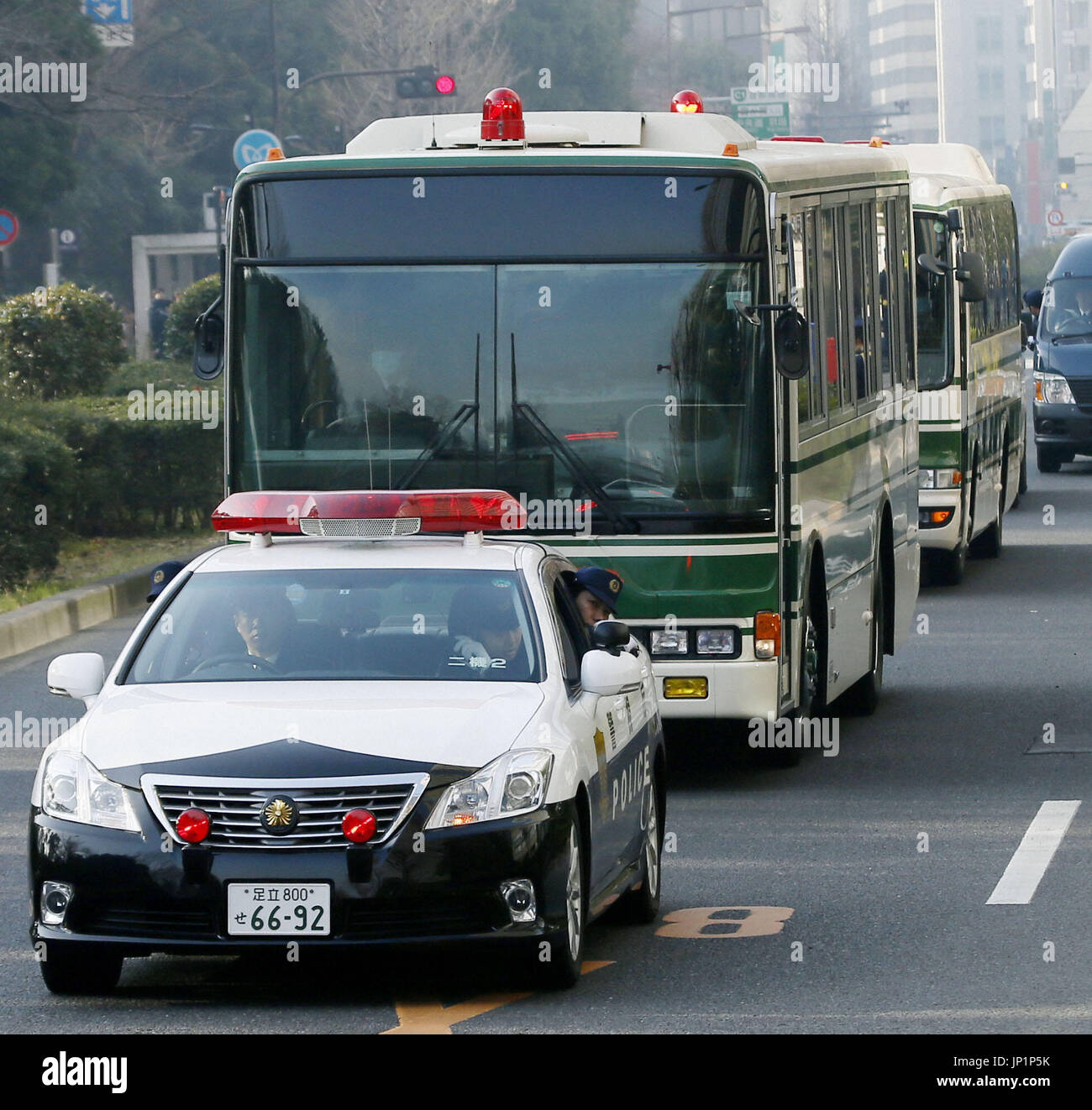 TOKYO, Japan - A police vehicle leads two buses, each believed to be ...