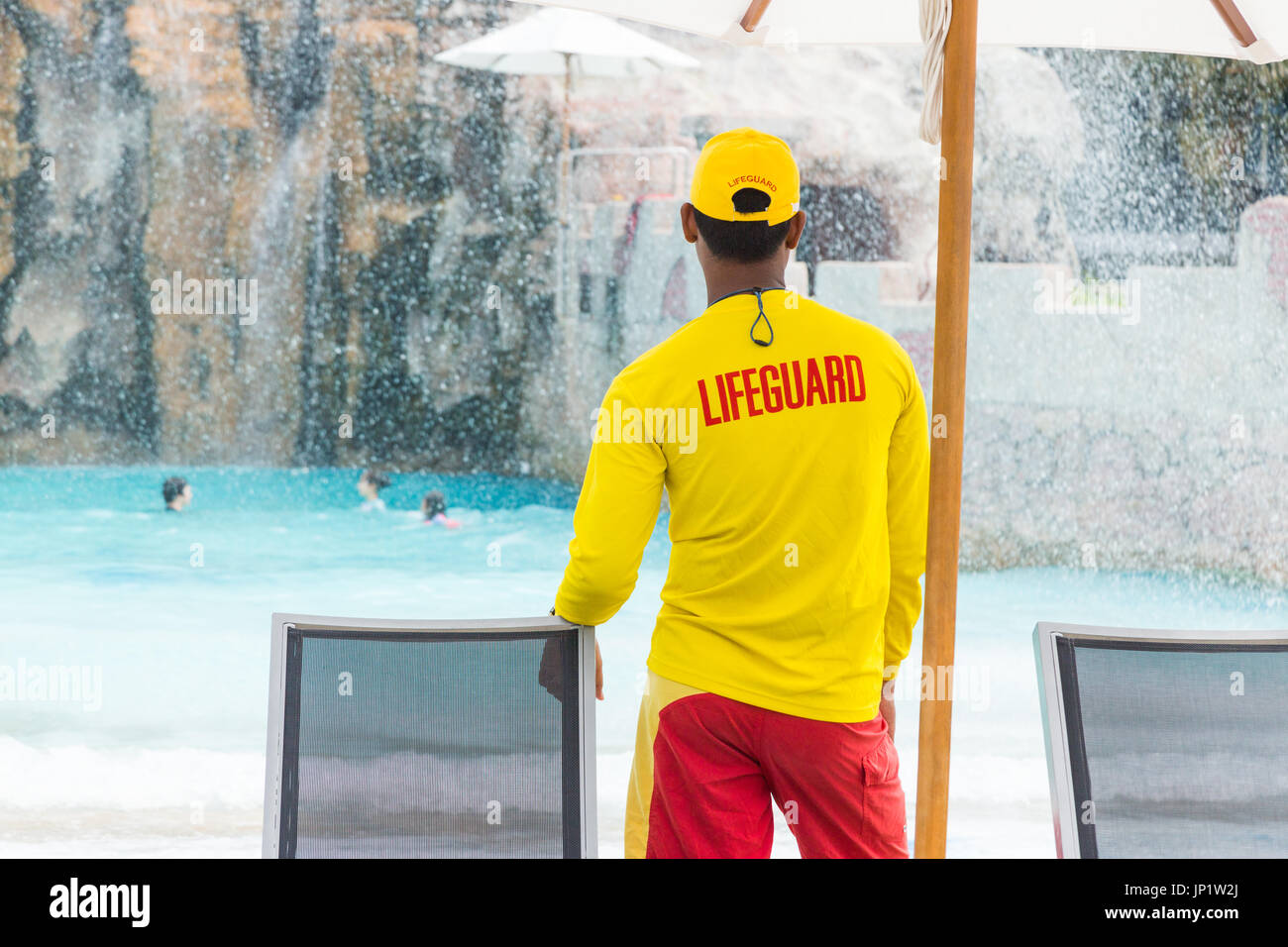 back side of lifeguard man wearing yellow lifeguard shirt and cap ...