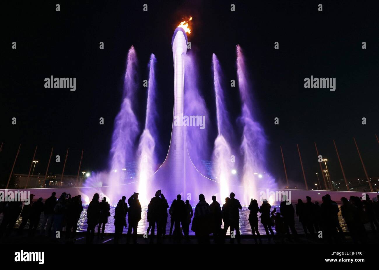 SOCHI, Russia - People watch the Olympic cauldron and water fountains ...