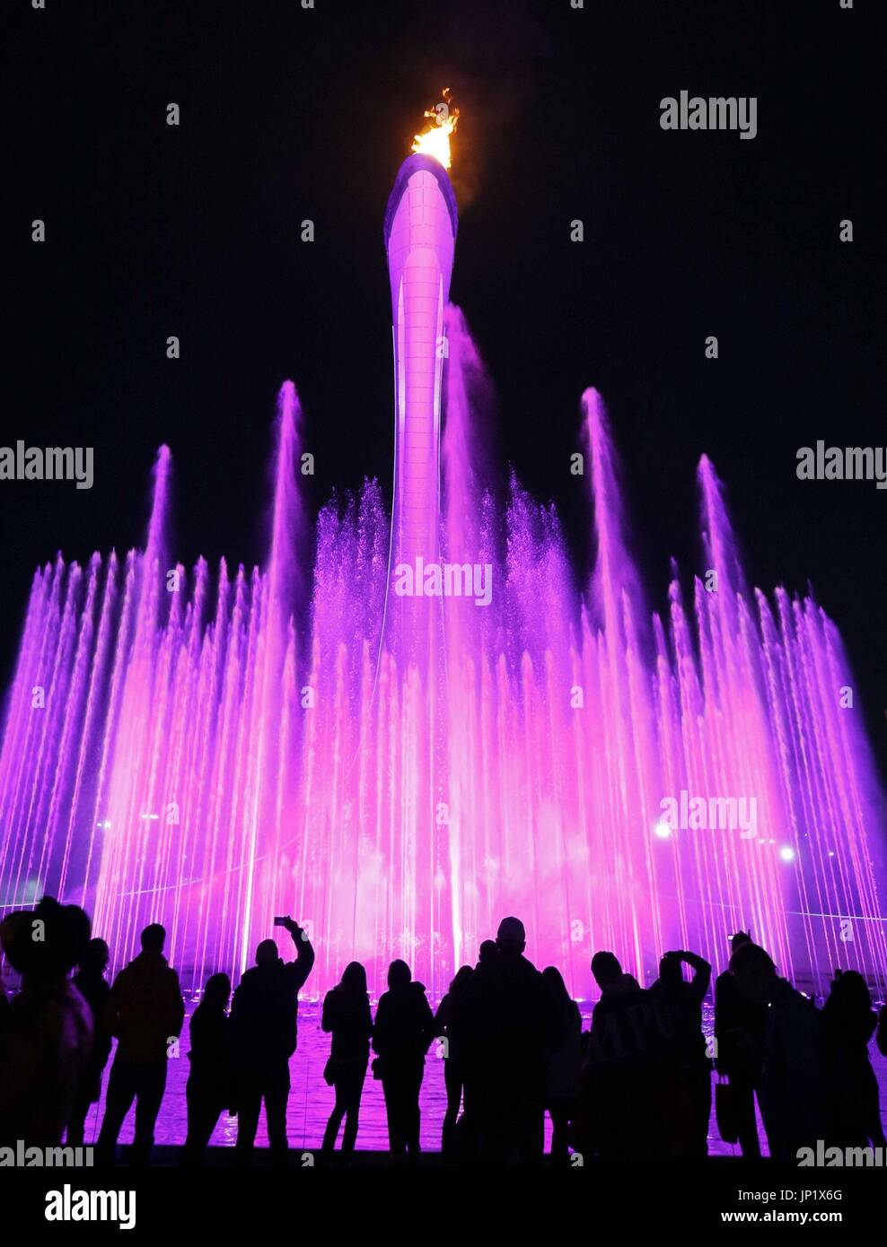 SOCHI, Russia - People watch the Olympic cauldron and water fountains ...